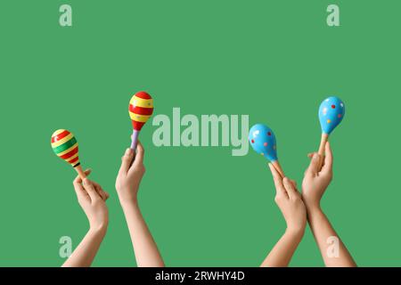 Female hands holding maracas on green background Stock Photo - Alamy
