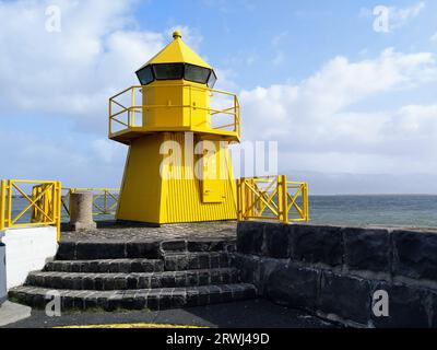 The historic yellow Hofoi lighthouse on the rocky shore of Reykjavik ...