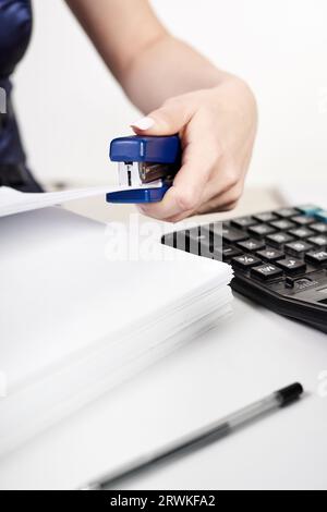 Female office worker stapling paper together in her office at work ...