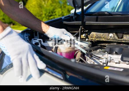 driver check the coolant level in the engine compartment of the car ...