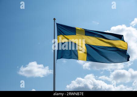 Sweden national flag waving on a flagpole, blue cloudy sky background ...