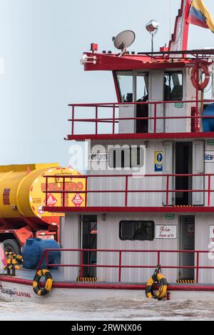 Transport tug boat on Napo River carrying large trucks and oil tankers ...