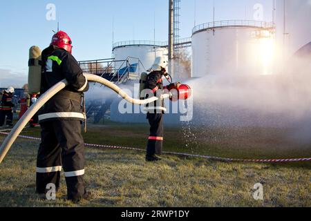 Firemen extinguish fire at oil tanks by foam spraying hose Stock Photo ...