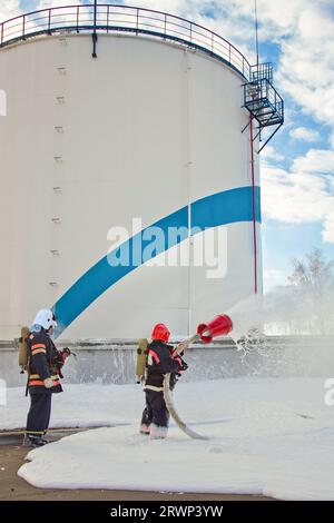 Firemen extinguish fire at oil tanks by foam spraying hose Stock Photo ...