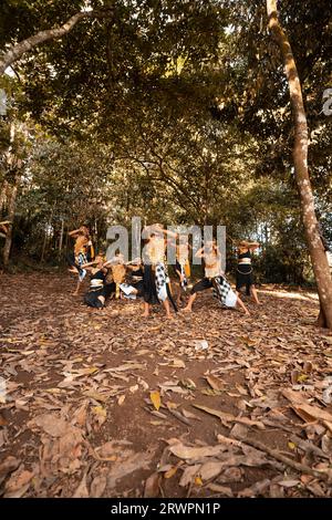 Balinese dancers with golden costumes and stripped pants dance together ...