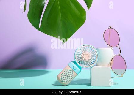 Plaster podium with portable electric fan and palm leaf on purple ...