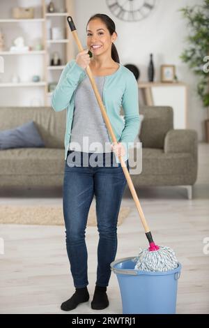 A beautiful young woman mops the floor with care, displaying her ...