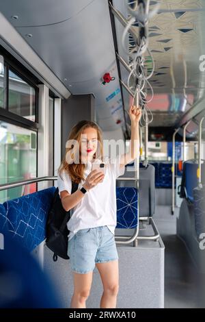 Young beautiful woman traveling by electric car having stop at charging ...
