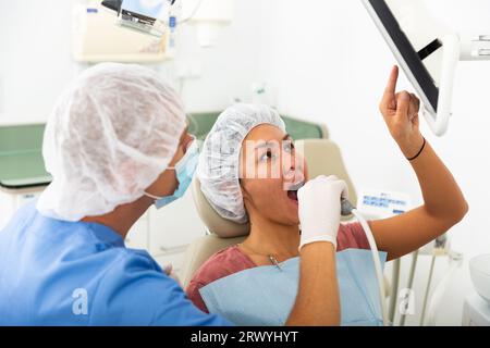 Qualified man dentist conducts an examination of a woman patient using ...