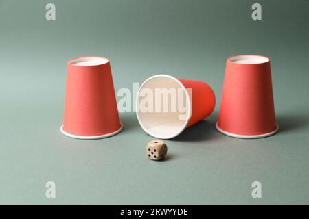 Three red cups and dice on light blue background. Thimblerig game Stock ...