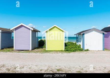 Colourful, windswept wooden bathing huts in the sand dunes on the beach ...