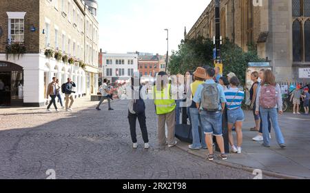 Mixed party of tourists with guide outside the University of Cambridge ...