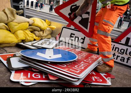 After temporary roadworks, a contractor sorts and stacks road signs and ...