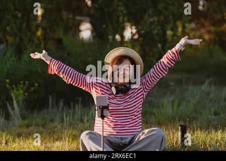 Happy Asian woman vlogging outdoors with smartphone for travel content ...