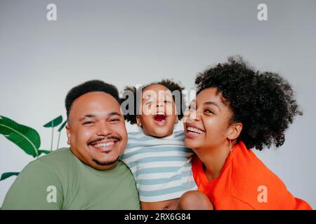 cheerful african american parents looking at curly daughter, banner ...