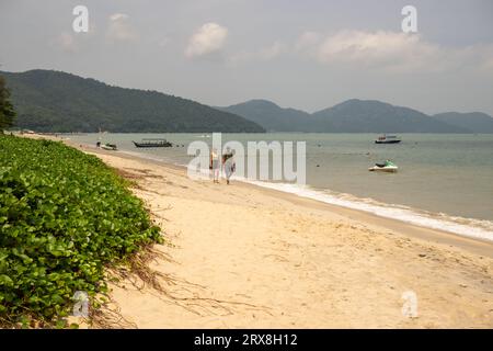 Couple walking along Batu Ferringhi Beach, Penang, Malaysia Stock Photo ...
