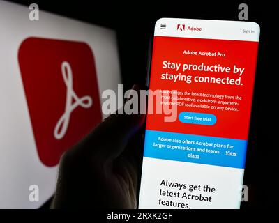 Person holding cellphone with logo of PDF management software Adobe ...