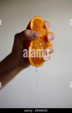 Man's hand squeezing orange Stock Photo - Alamy