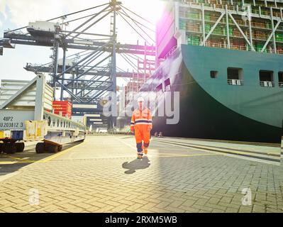 Dock worker walking beside cargo ship at Port of Felixstowe, England ...