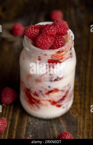 Fresh milk yogurt with whole fresh raspberries, a glass jar with ...