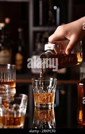 Woman pouring tasty rum from bottle into glass at table in bar Stock ...