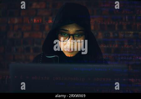 Hacker, woman in basement with laptop and information technology, phishing and cyber crime with ...