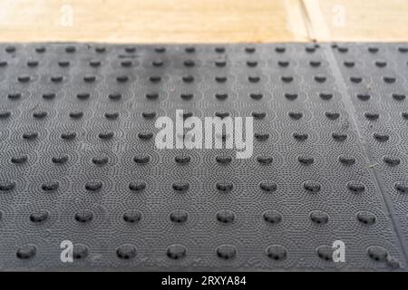 Close up image of a gray detectable warning surface, tactile plate at a ...