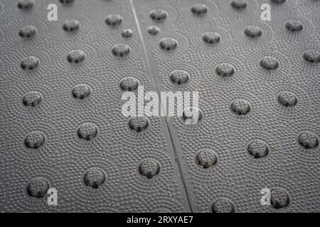 Close up image of a gray detectable warning surface, tactile plate at a ...