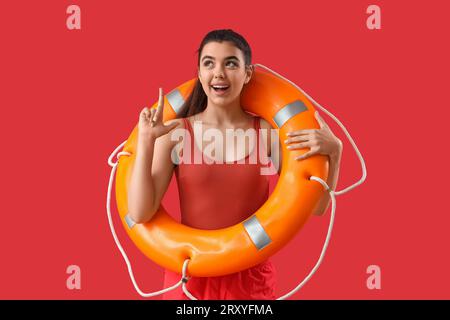 Female lifeguard with ring buoy pointing at something on yellow ...