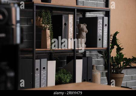 Shelf unit with document folders and plants near green wall Stock Photo ...