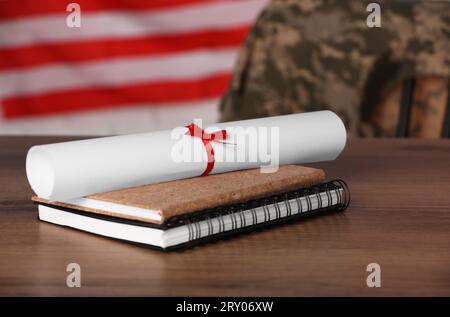 Diploma and notebooks on wooden table against flag of USA. Military ...