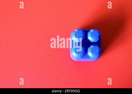 Buildable blue plastic block on a red background. Concept of loneliness ...