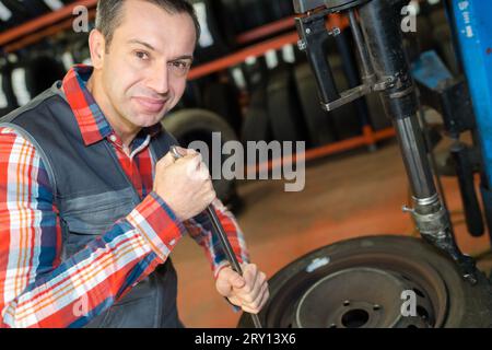 car mechanic screwing or unscrewing car wheel Stock Photo - Alamy