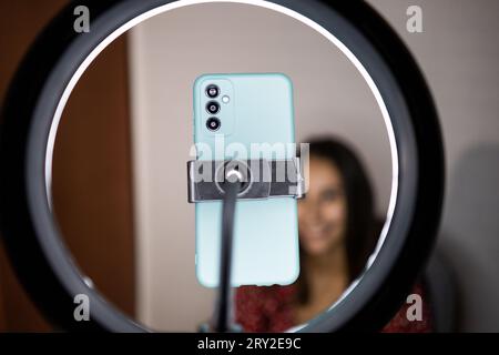 blurred phone holder with ring lamp near fashion blogger taking selfie ...