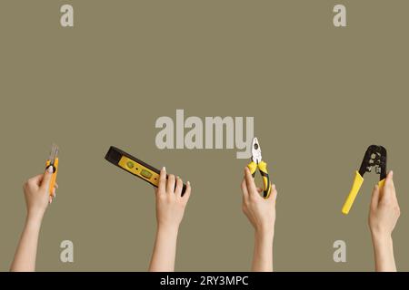 Electrician hands with tools on green background Stock Photo - Alamy