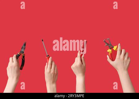 Electrician hands with tools on red background Stock Photo - Alamy