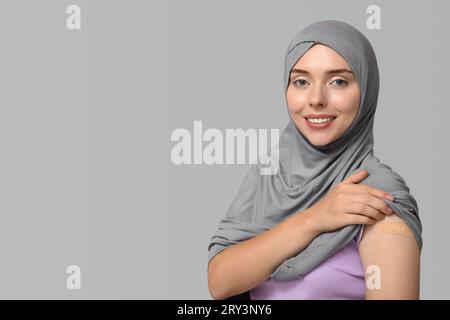 Muslim woman with medical patch on arm against blue background with ...
