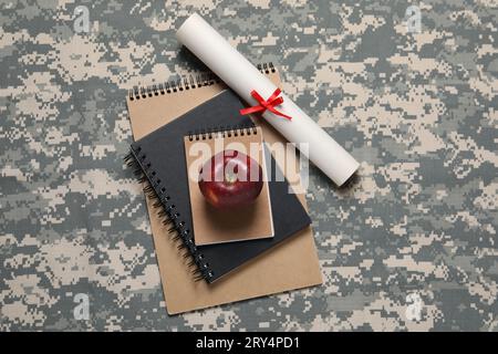 Apple and diploma on camouflage background, flat lay with space for ...