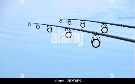 Diminishing perspective of fishing rods over blue water background with ...