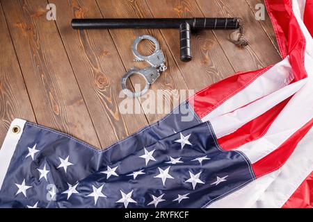silver metal handcuffs and police nightstick over US flag on flat ...