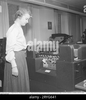 In the 1950s. A female clerk at punch card reader machine overlooking ...