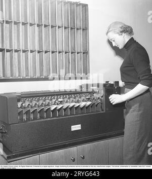 In the 1950s. A female clerk at punch card reader machine overlooking ...