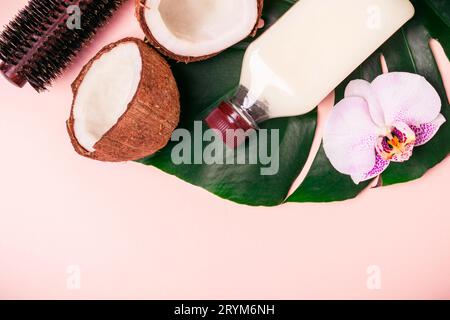 Coconut oil and halves of fresh coconut on a pink background. Hair care ...