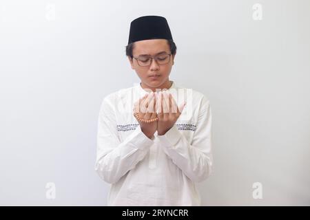 Portrait of young millennial Asian muslim man praying earnestly with ...