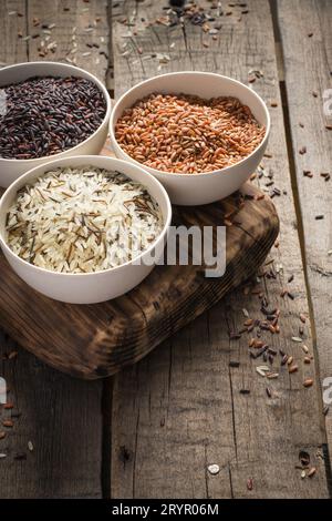 Mix of different varieties of rice in bowl on a wooden background ...