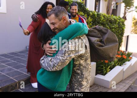 Happy diverse friends with flags welcoming home male soldier friend ...