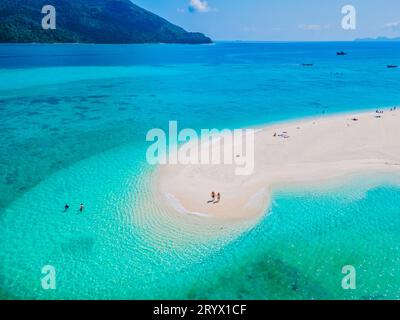 men and women walking on a sandbar in the ocean of Koh Lipe Southern ...