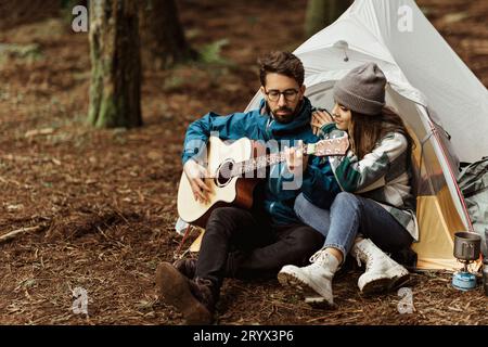 Young couple playing music while walking in the forest. Hiking concept ...