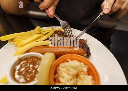Man eating Grilled Meats stake from plate. hand holding knife and fork ...
