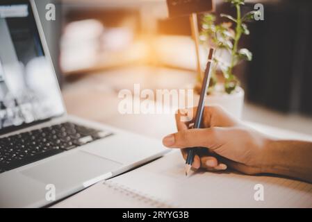 Business people using a pencil noting over laptop Stock Photo - Alamy